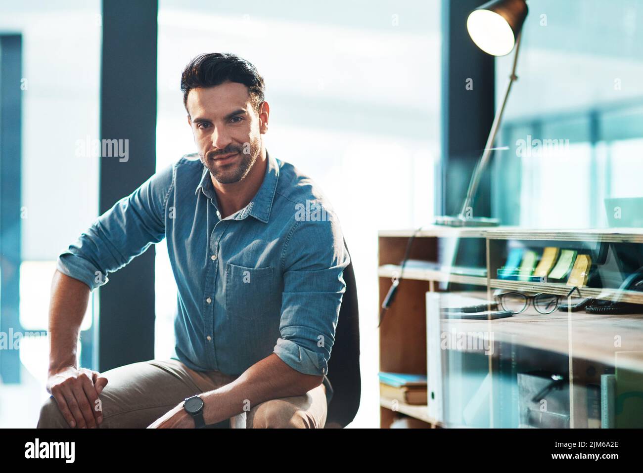 A confident, serious and powerful male entrepreneur sitting in a modern ...