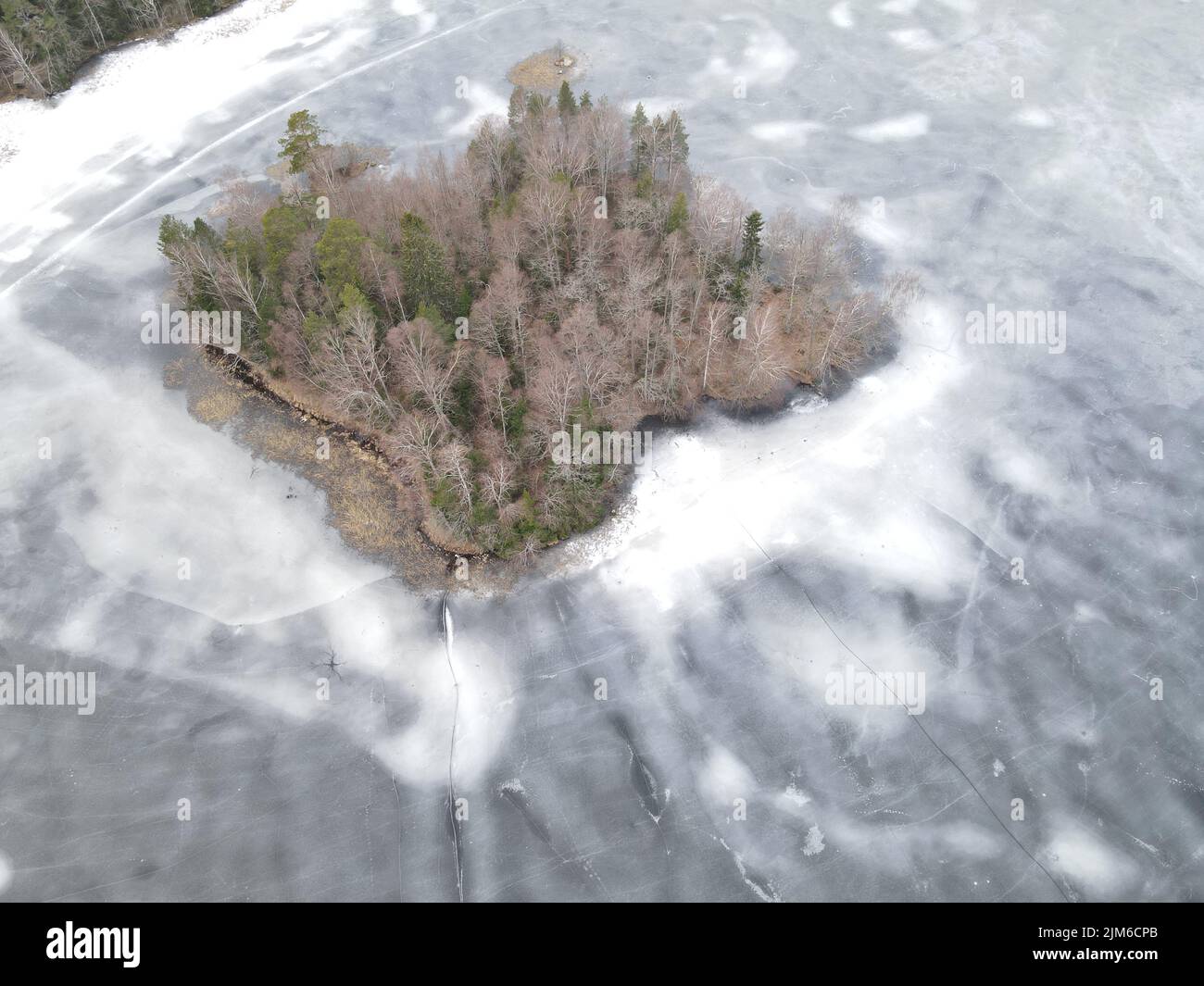 A bird-eye view of ice covered lake and a little grove in the middle ...