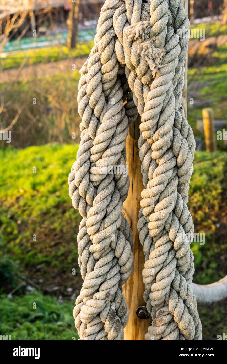 A vertical shot of Large ship ropes tied to a wooden post in a London ...