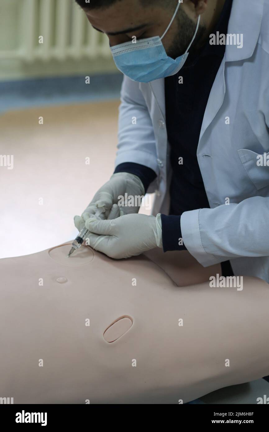 A medical student wearing a protective face mask is seen learning to ...