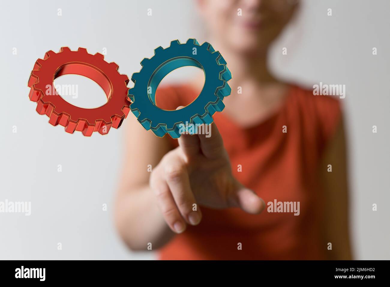 A person tapping on a floating render of turning gears Stock Photo - Alamy