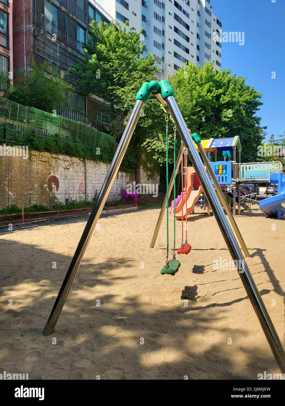 A vertical shot of empty swings with colorful seats in a playground ...