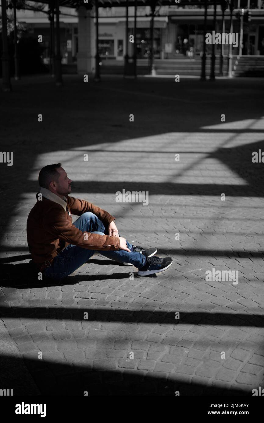 A vertical shot of a young male sitting in a shadow in Montreux ...