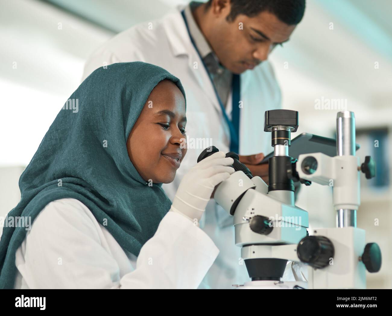 Conducting controlled tests. a young scientist using a microscope while ...
