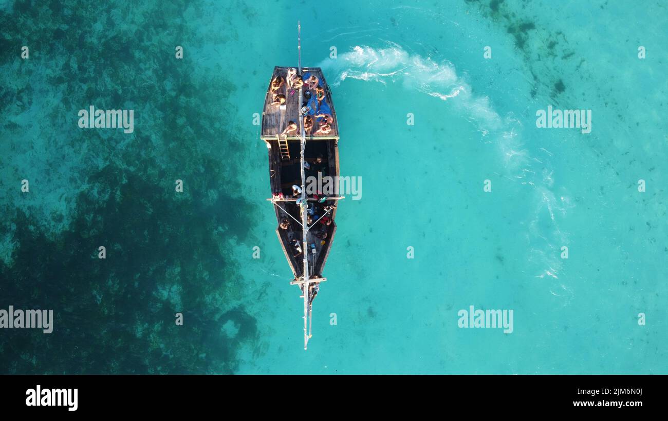 The top view of the boat with tourists on the turquoise water surface ...
