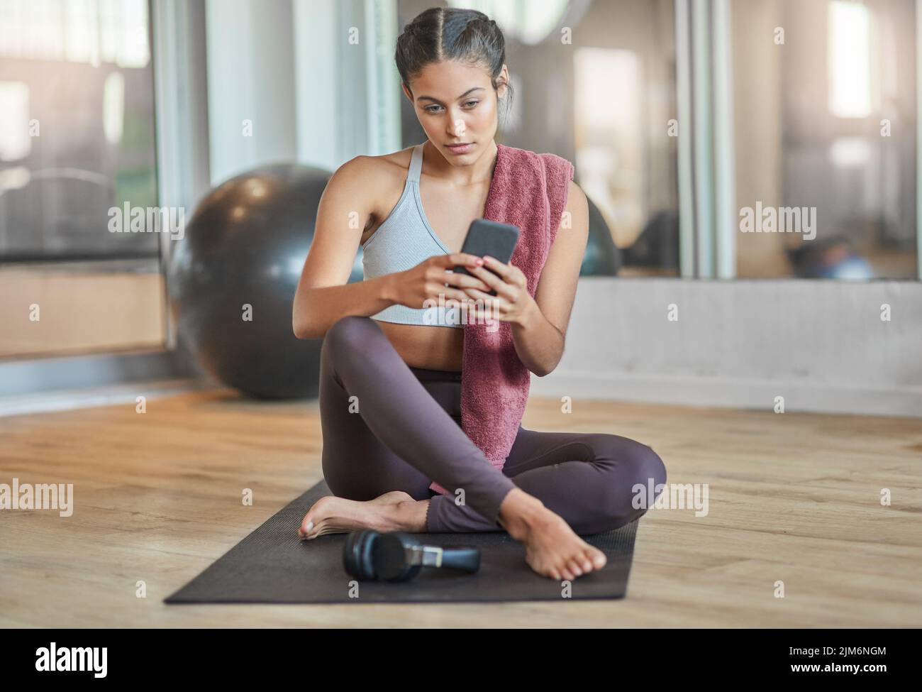 Just at the gym for an hour. Full length shot of an attractive young female athlete checking her ...