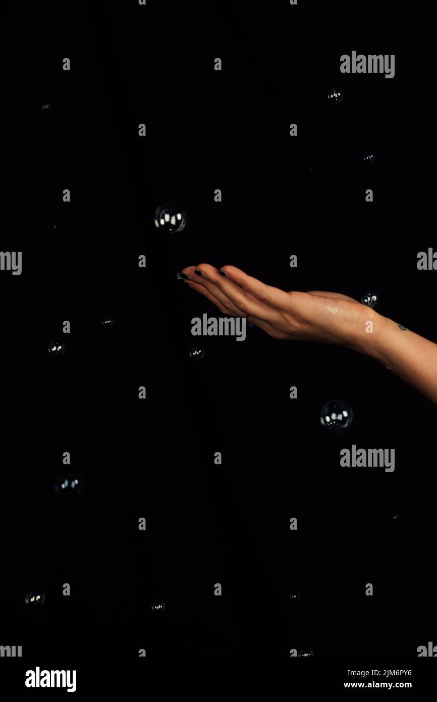 woman's hand reaching from the right to catch a touchable bubble, black ...