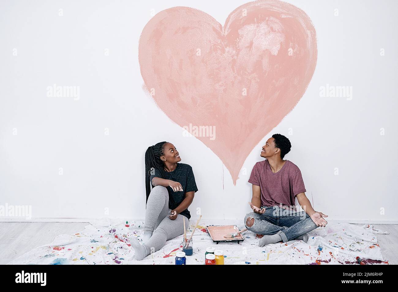 Fill your home with lots of love. a young couple painting a heart on a ...