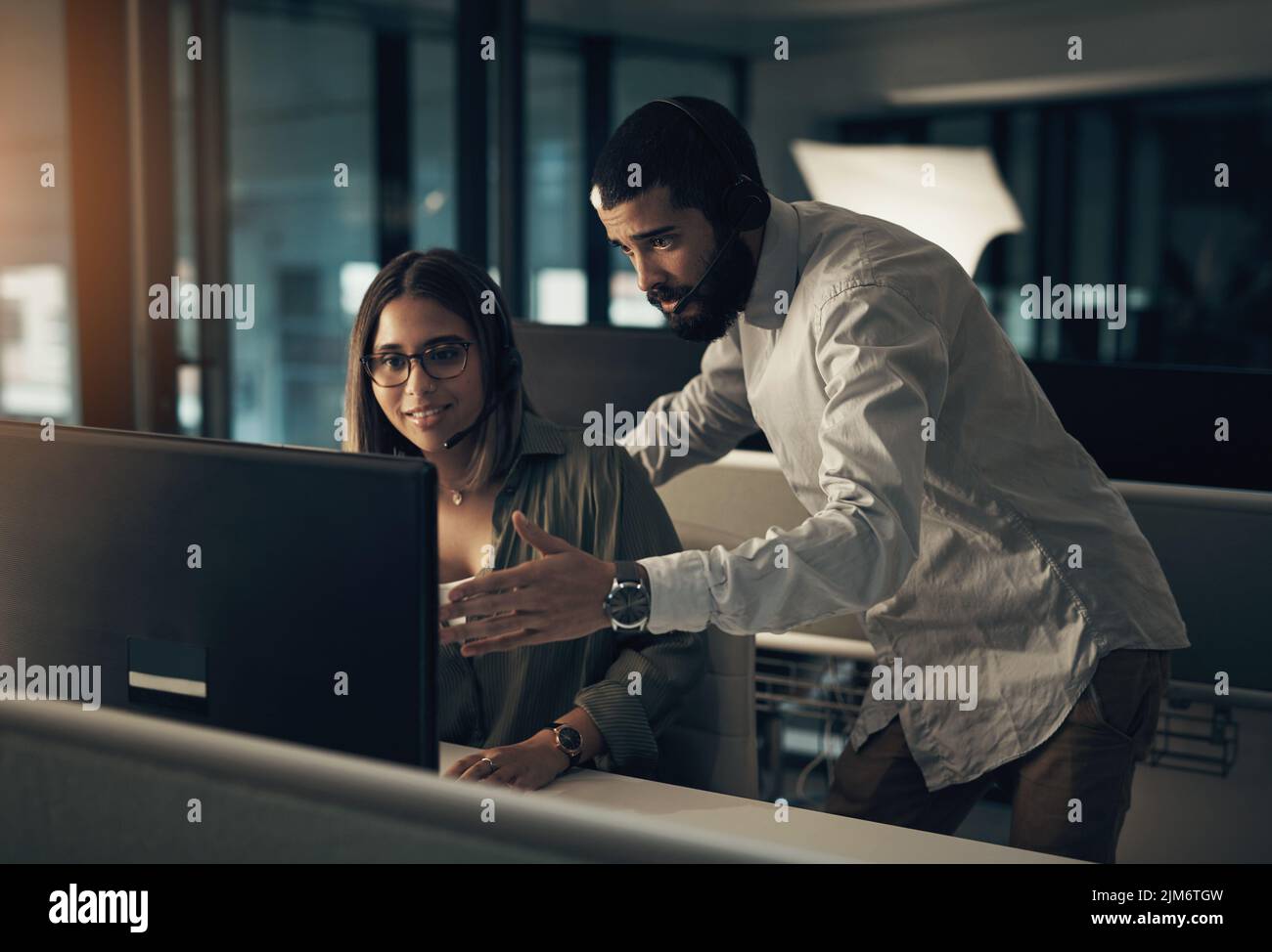 Solving queries together. two call centre agents working together in an ...