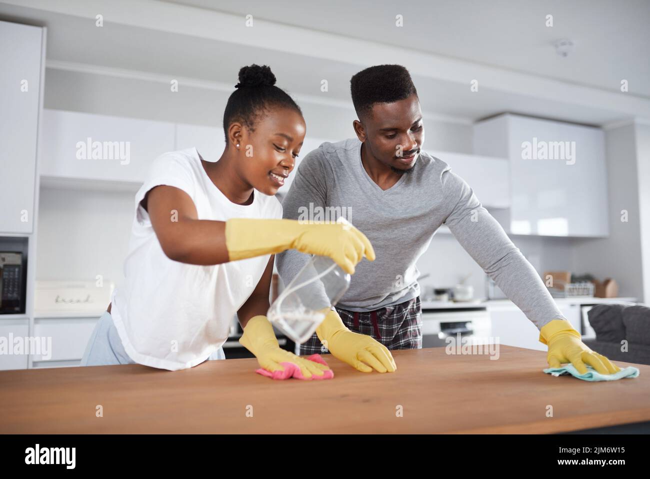 Every spray keeps the germs away. a young couple cleaning the kitchen ...
