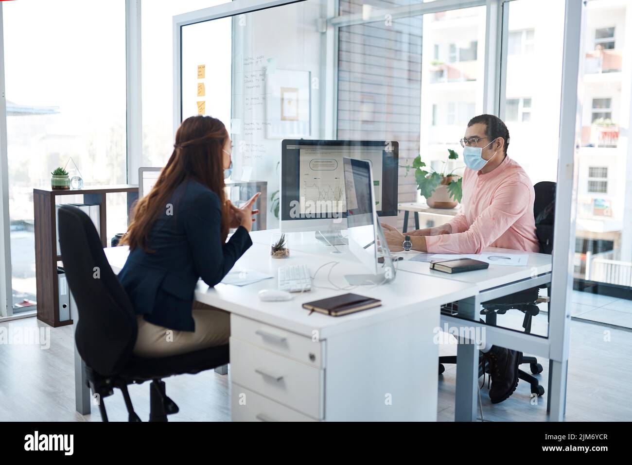 Safely working face-to-face. two businesspeople wearing face masks ...