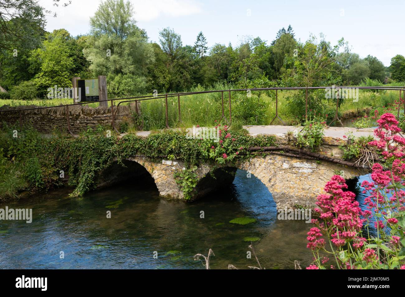 The beautiful stone footbridge covered with flowers. Bibury, England ...