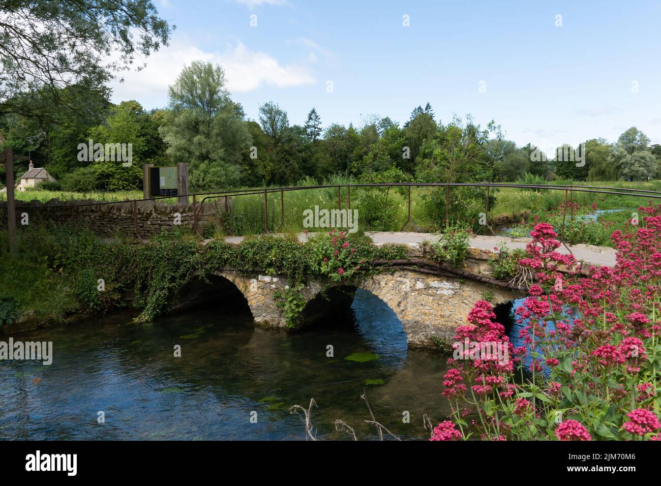 The beautiful stone footbridge covered with flowers. Bibury, England ...