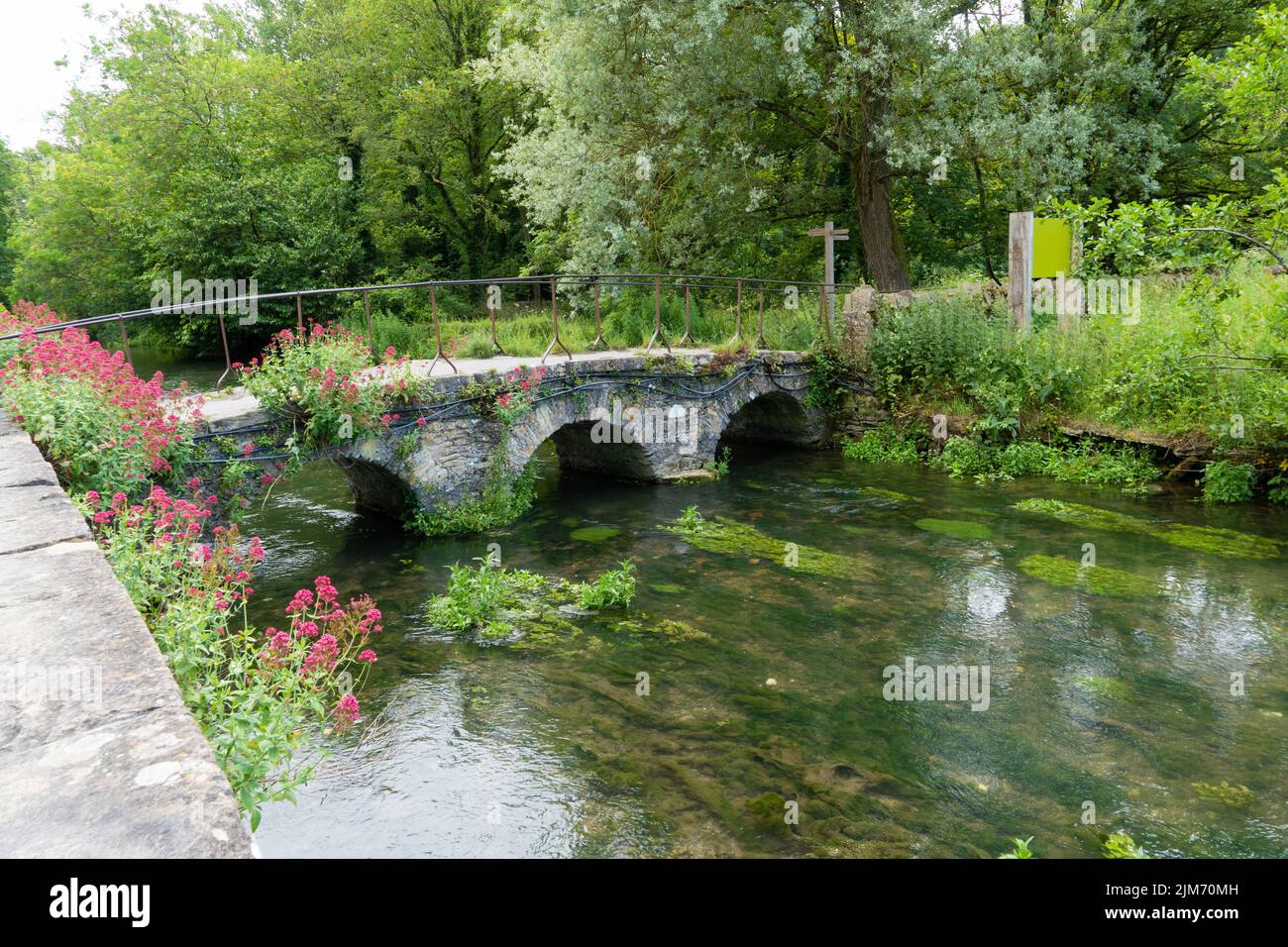 The beautiful stone footbridge covered with flowers. Bibury, England ...