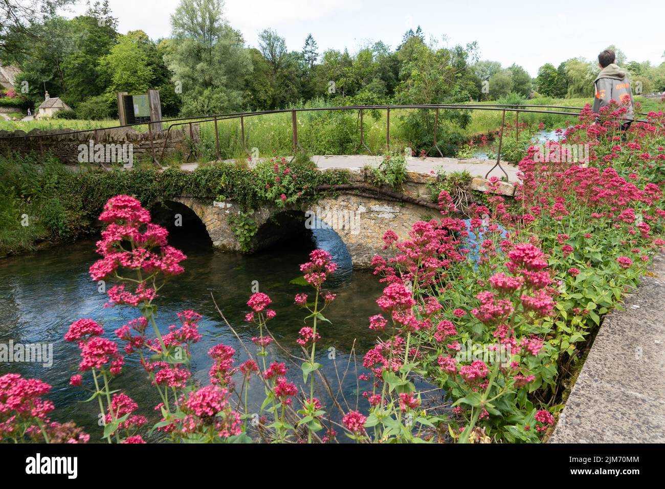 The beautiful stone footbridge covered with flowers. Bibury, England ...