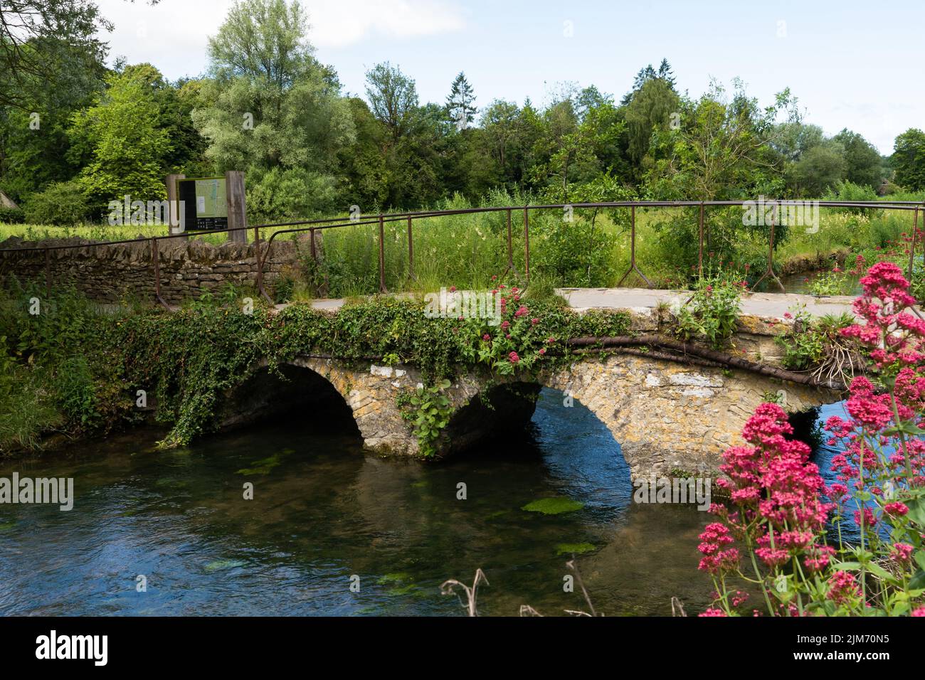 The beautiful stone footbridge covered with flowers. Bibury, England ...