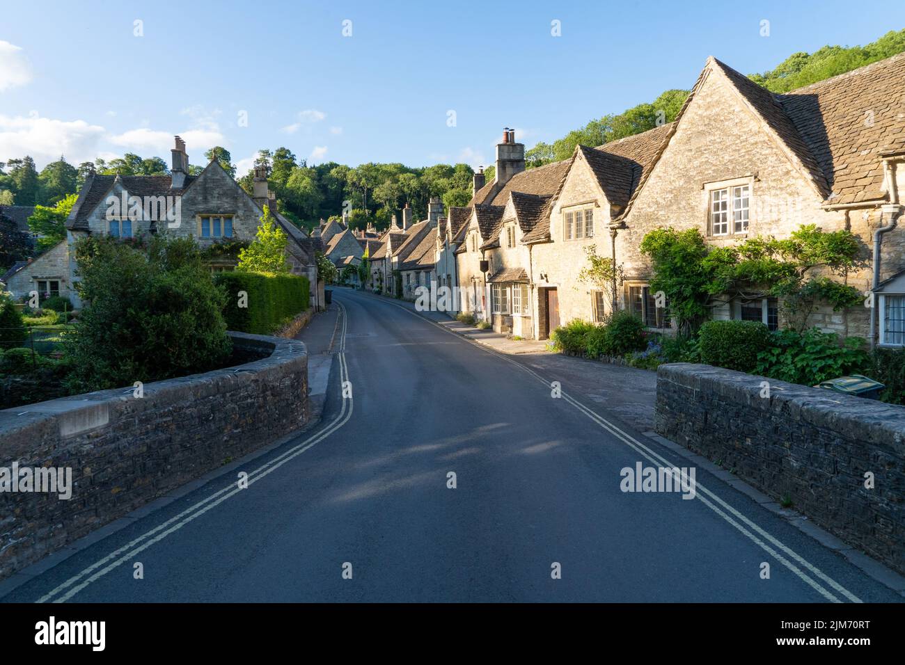 The brown stone cottages surrounded by green vegetation. Castle Combe ...