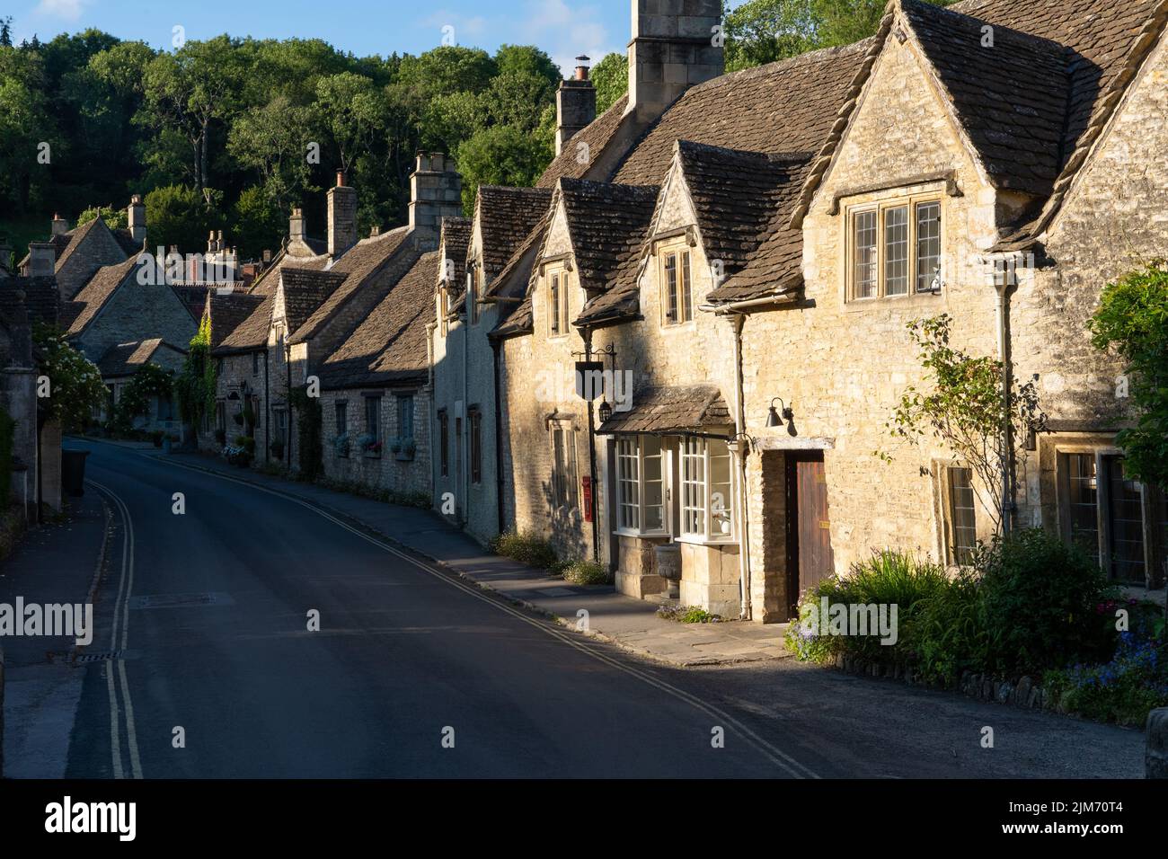 The brown stone cottages surrounded by green vegetation. Castle Combe ...