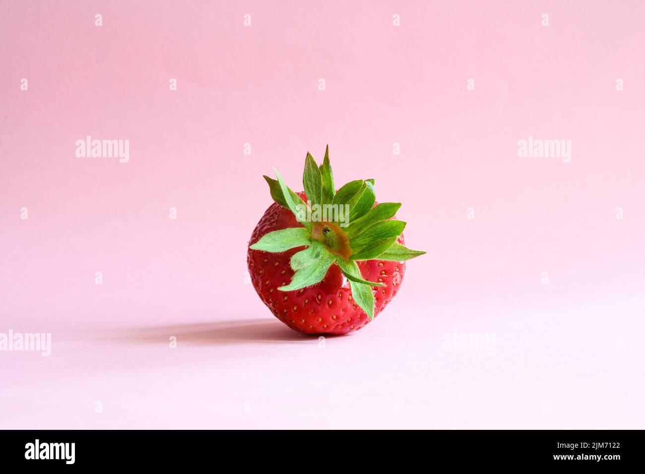 Red fresh strawberry with green leaves from above in front of pink ...