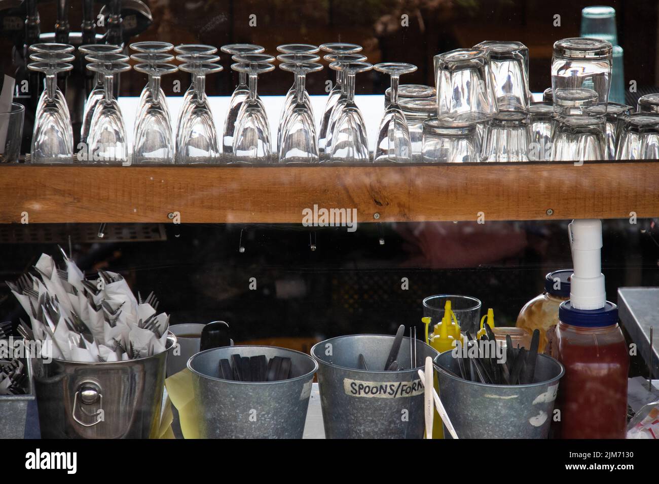 A closeup of cafe cutlery on shelves. The glasses, forks in the metal ...
