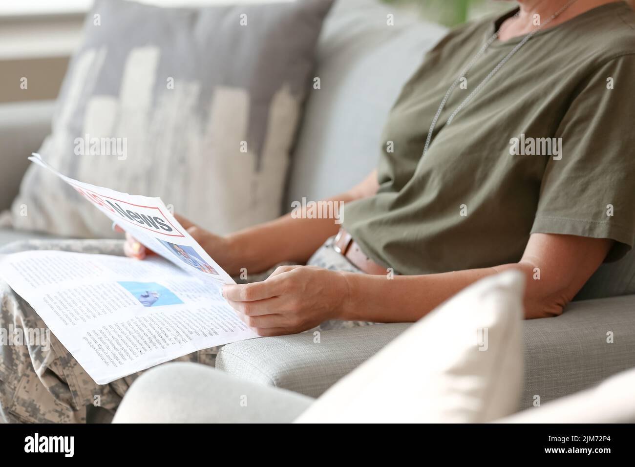 Mature female soldier reading newspaper at home Stock Photo - Alamy