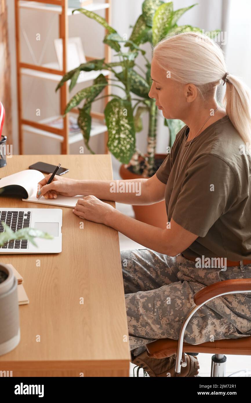 Mature female soldier writing in notebook at home Stock Photo - Alamy