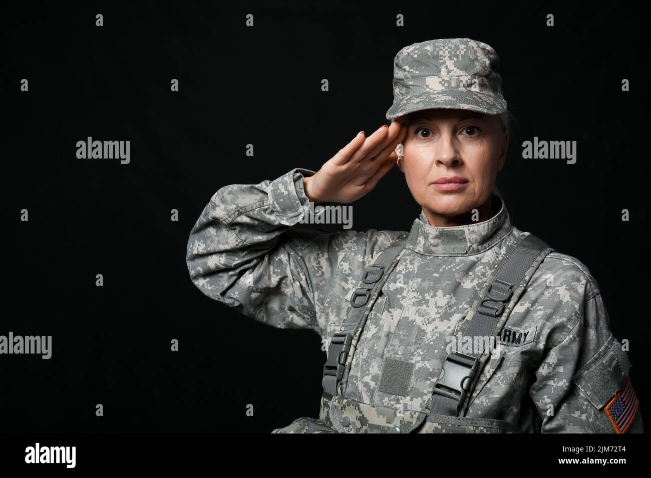 Mature female soldier saluting on black background Stock Photo - Alamy