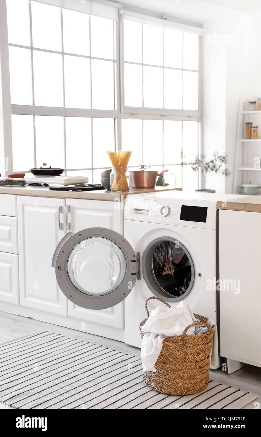 Modern washing machine and laundry basket in light kitchen Stock Photo ...