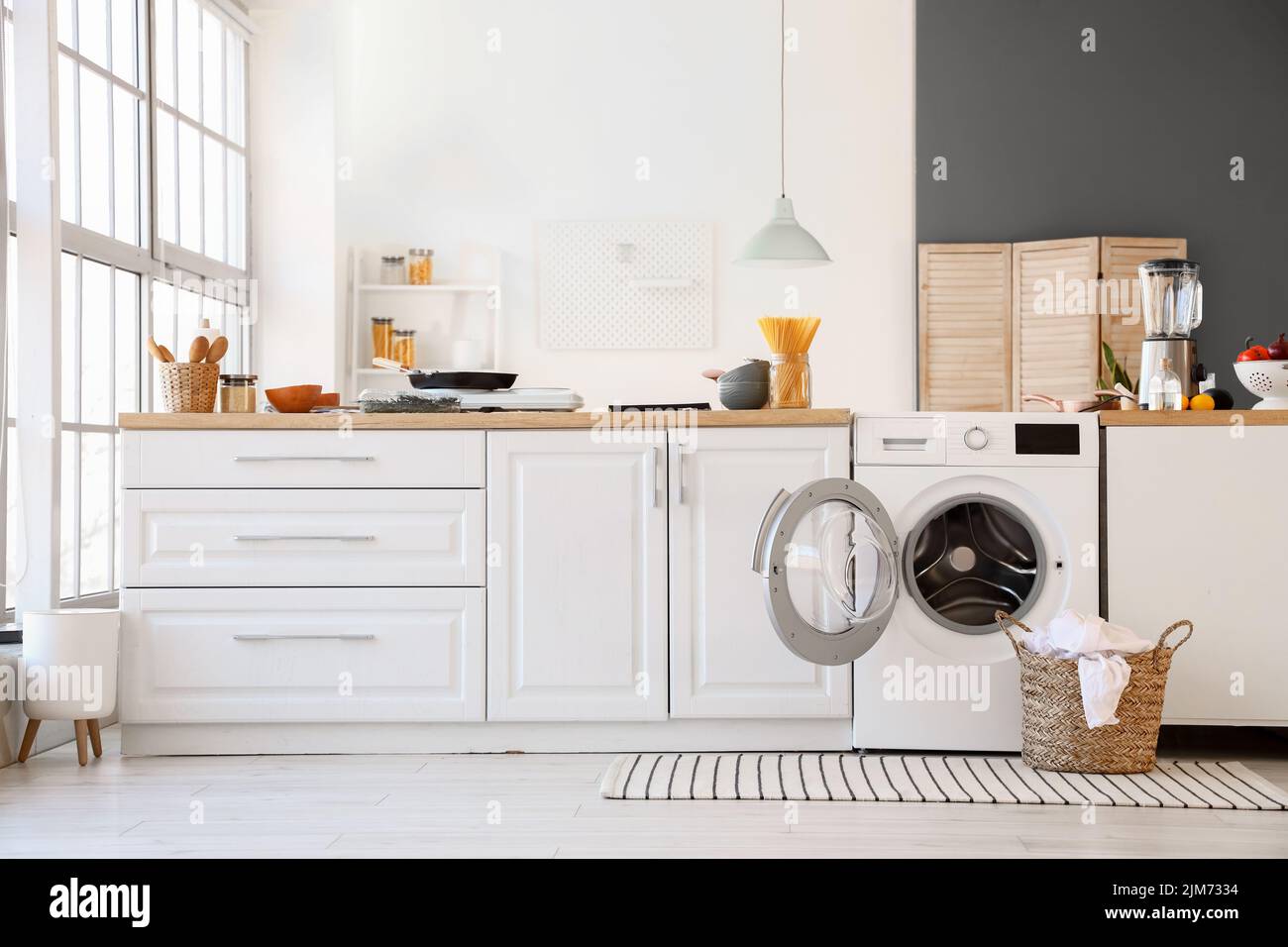 Interior of light kitchen with washing machine, laundry basket and ...
