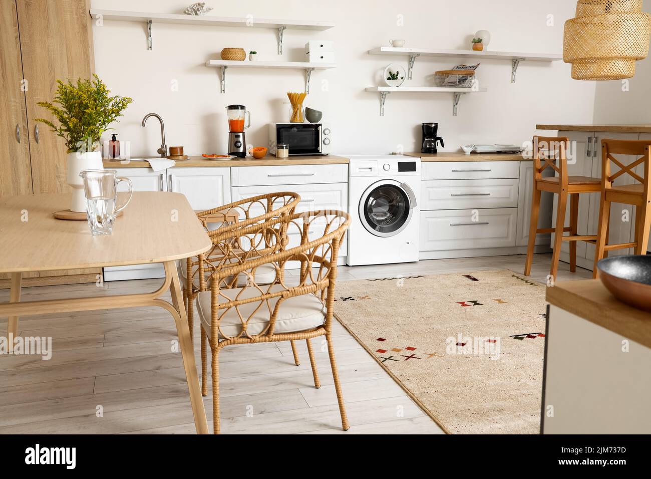 Interior of light kitchen with washing machine, counters and dining ...