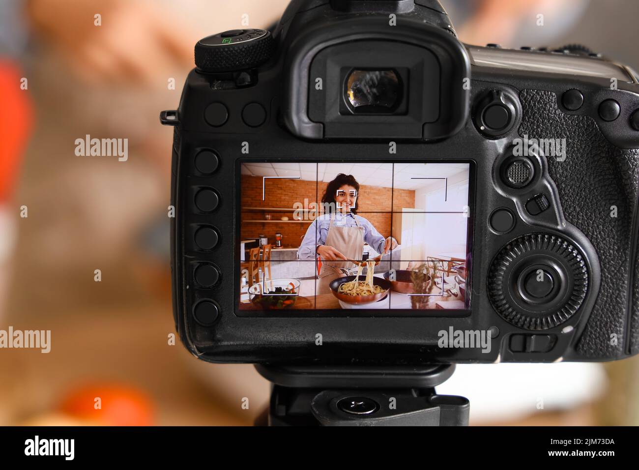 Young woman cooking pasta on display of photo camera in kitchen ...