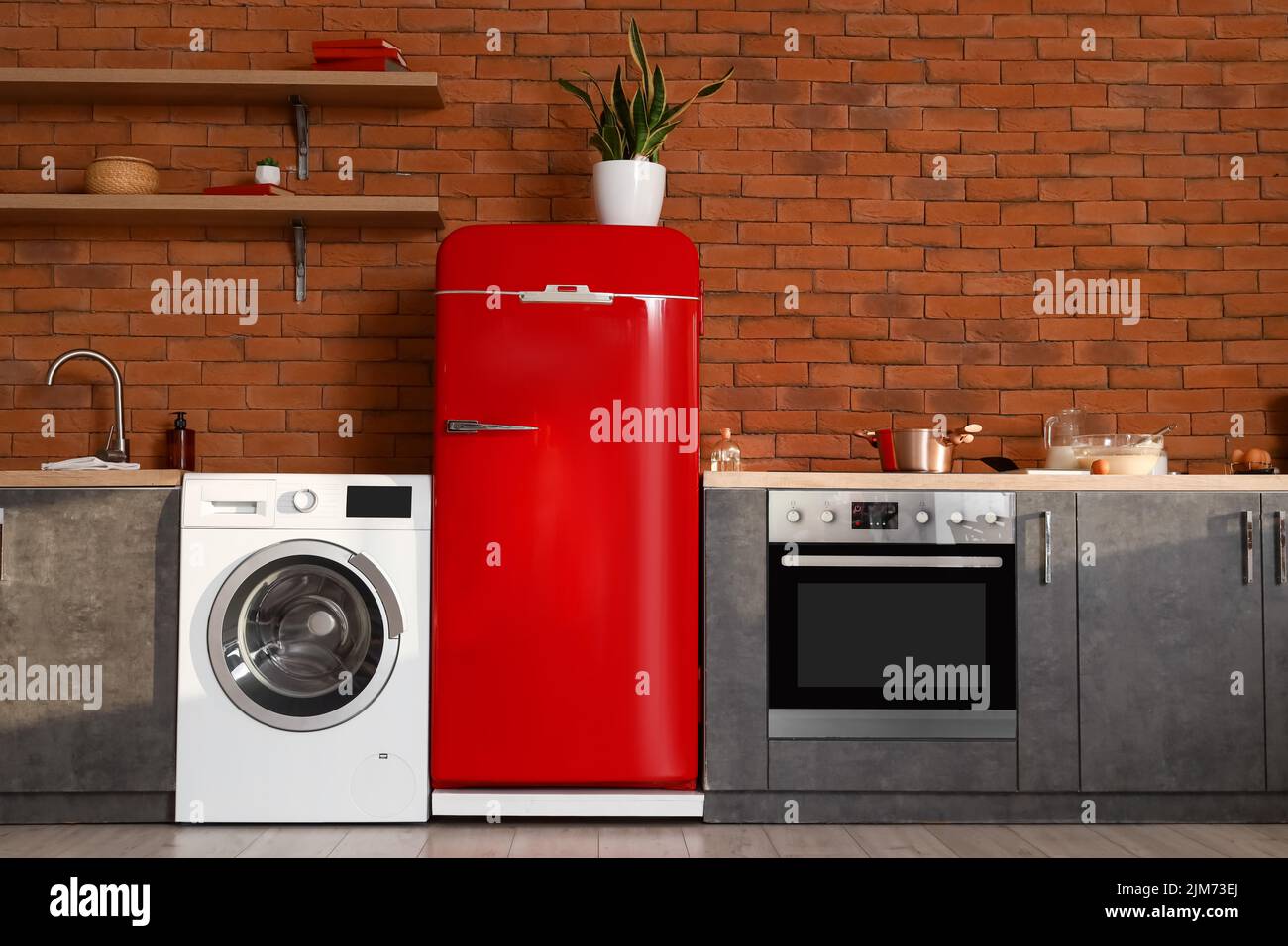 Interior of stylish kitchen with washing machine, fridge and counters ...
