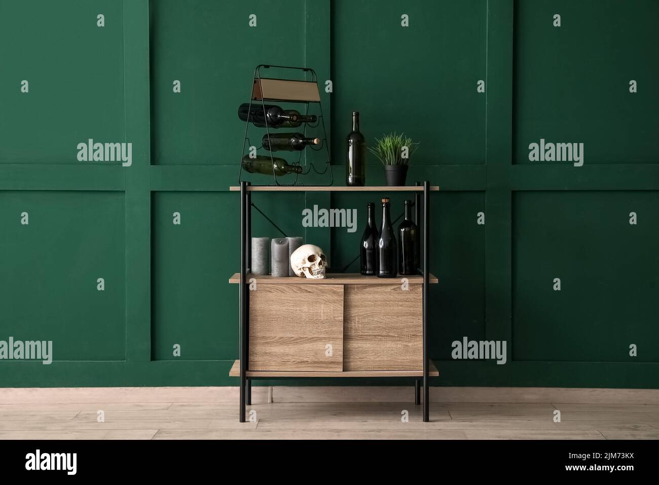 Shelving unit with wine bottles, human skull and candles near green ...