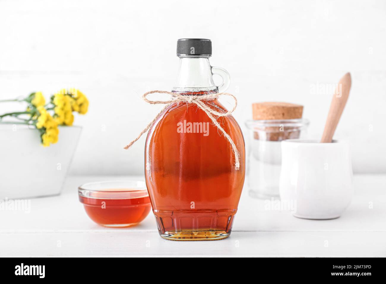 Glass bottle of maple syrup on light background Stock Photo - Alamy