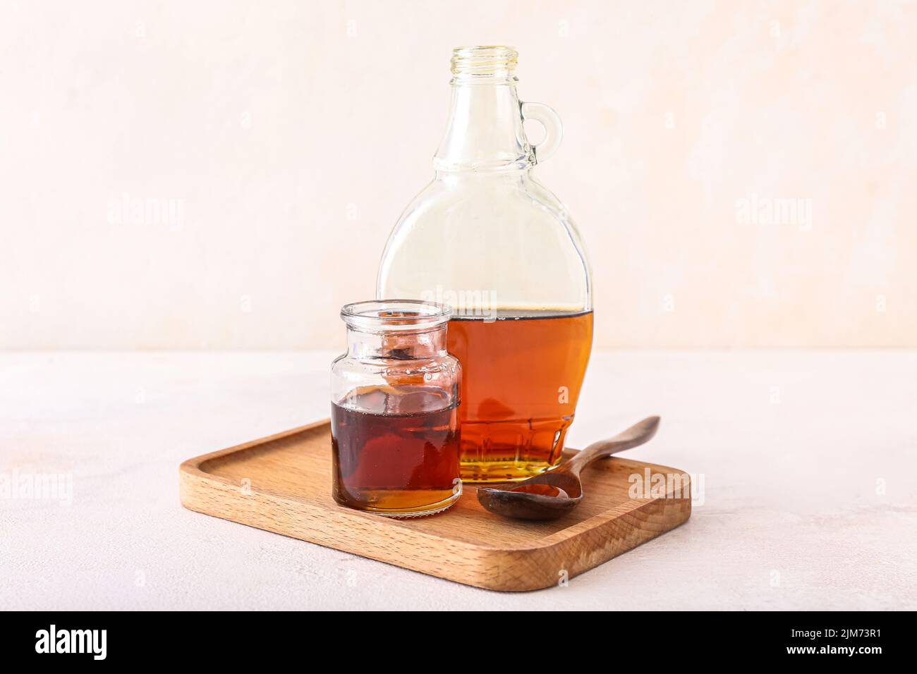 Wooden board with bottles of maple syrup on light background Stock ...