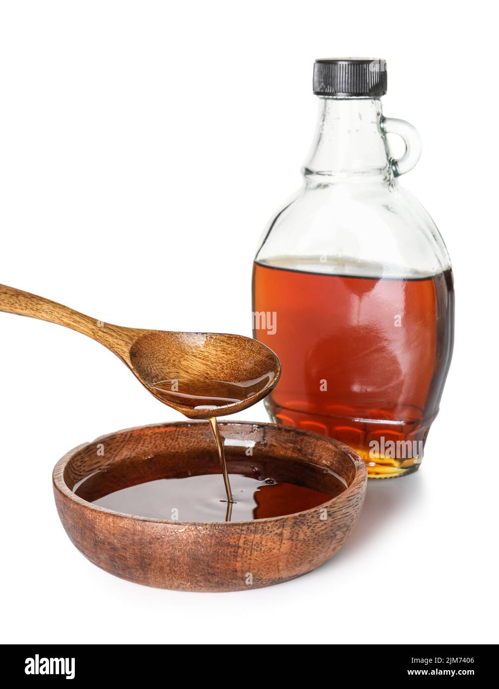 Pouring of tasty maple syrup from spoon into bowl on white background ...