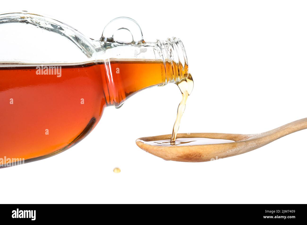 Pouring of tasty maple syrup from bottle into spoon on white background ...