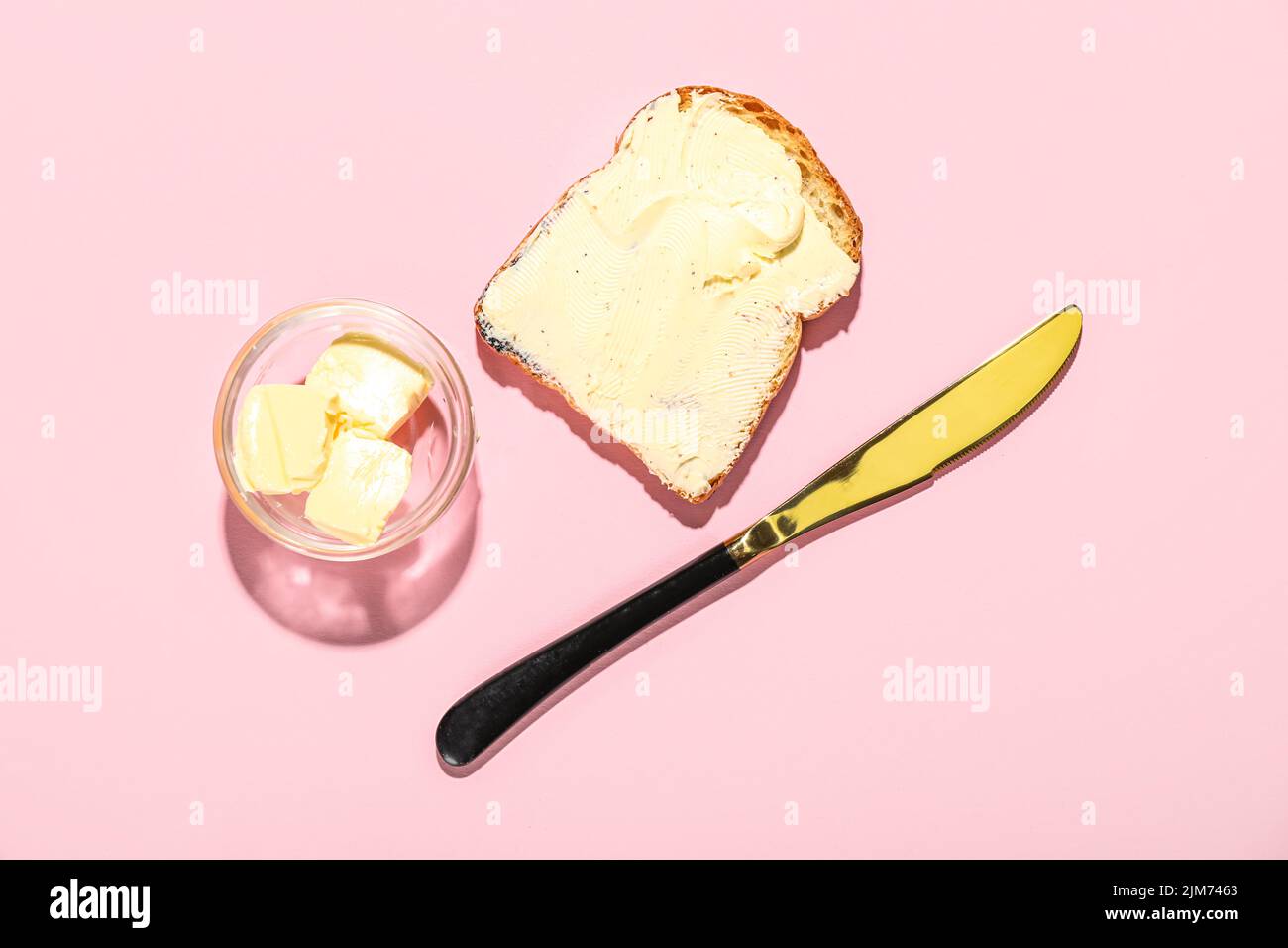 Crispy toast with butter and knife on pink background Stock Photo - Alamy