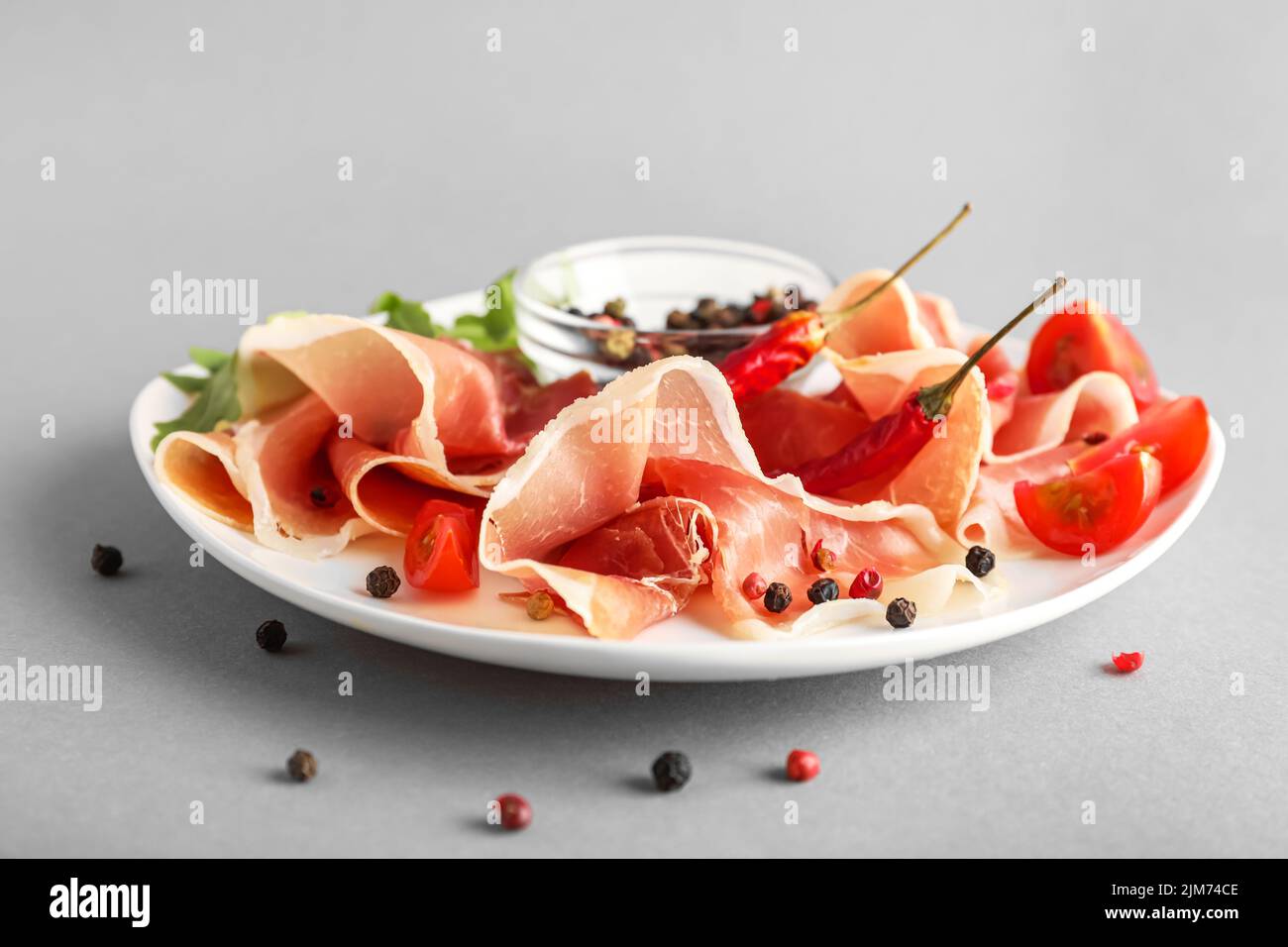 Plate of delicious jamon and peppercorns on light background Stock ...