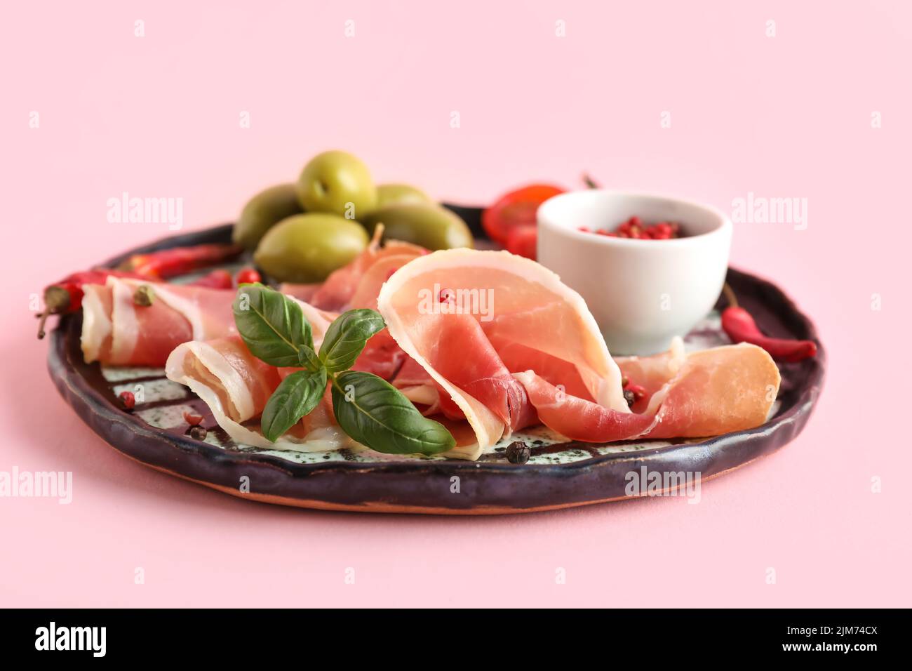 Plate with delicious jamon on pink background Stock Photo - Alamy