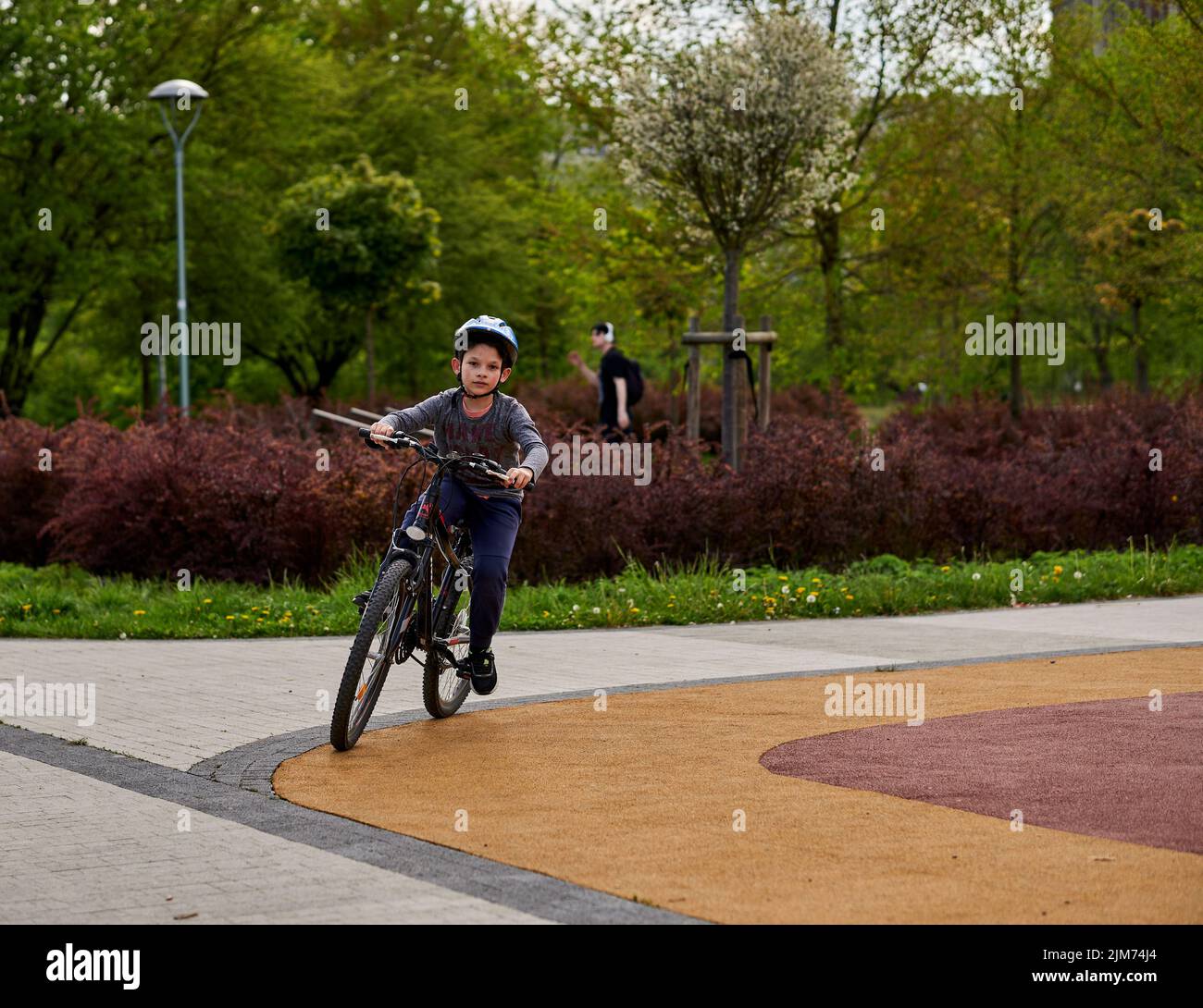 A little boy with safety helmet riding a bicycle on the Rataje park on ...