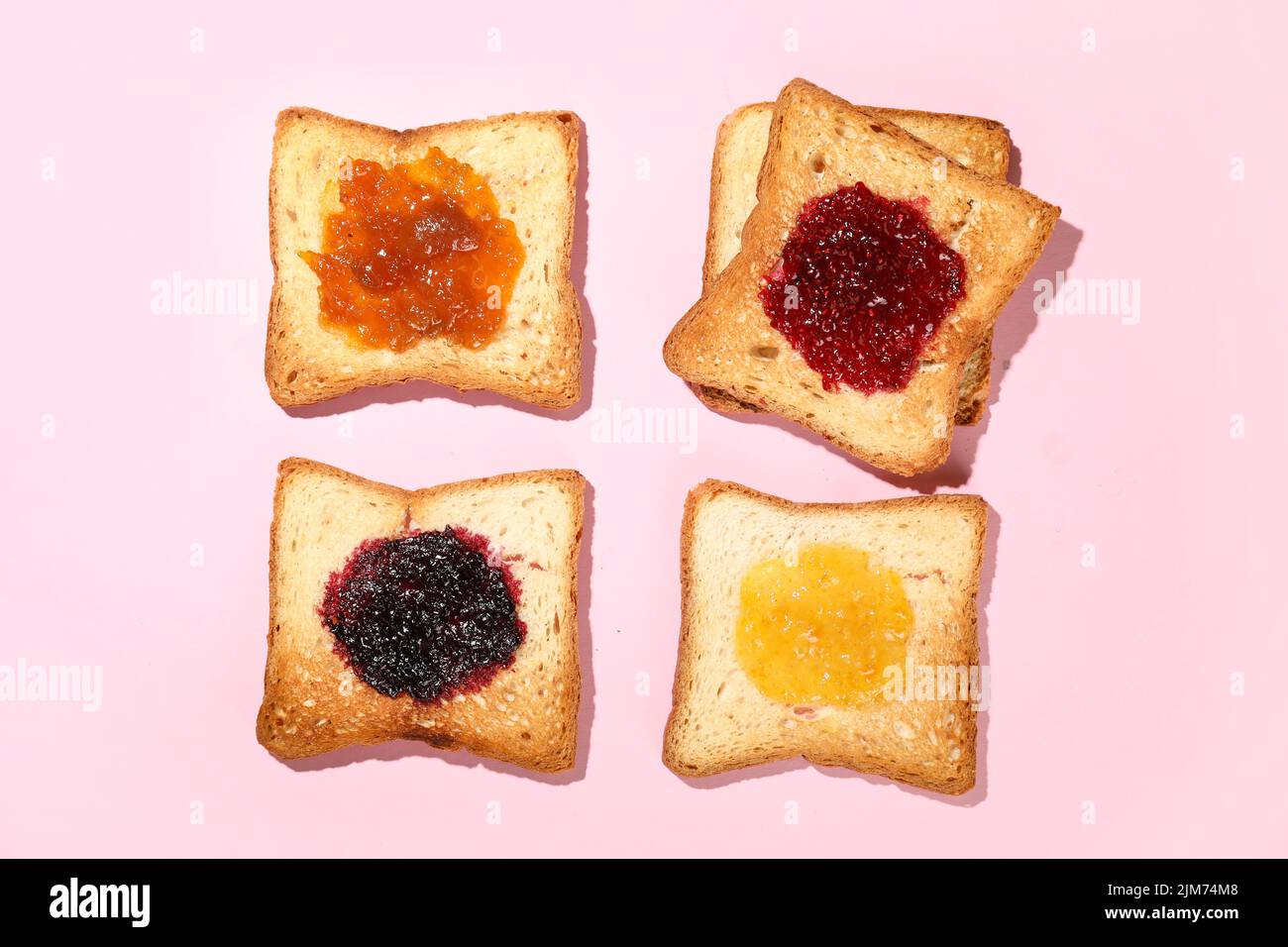 Toasts with different jams on pink background Stock Photo - Alamy