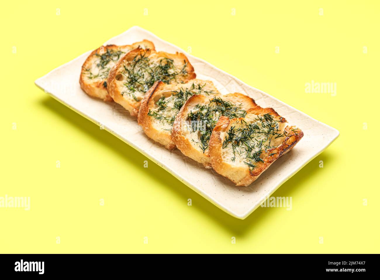 Plate with slices of toasted garlic bread on yellow background Stock ...