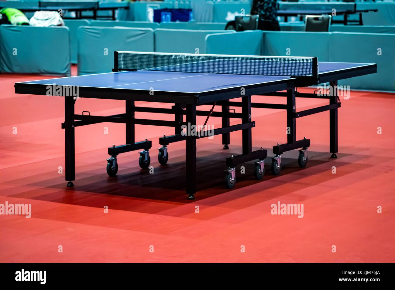 Blue table tennis or pingpong table is settle on a red, orange floor of ...