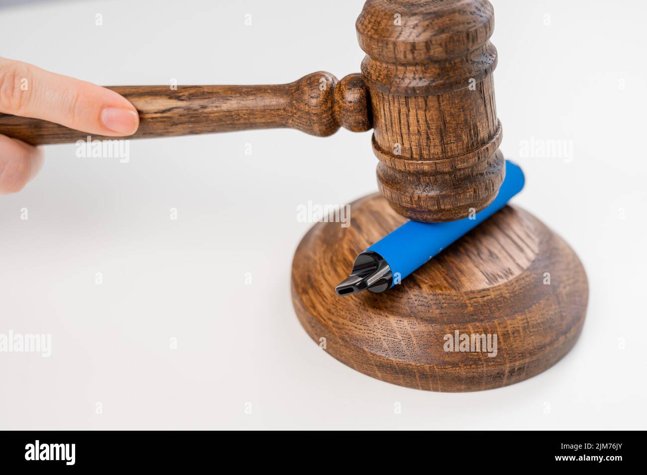 Judge hammering disposable vape with referee's gavel on white table ...