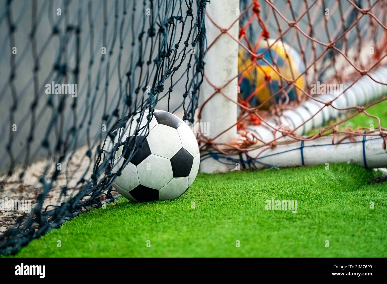 Classical football or soccer ball and goal lying on the artifinal grass ...