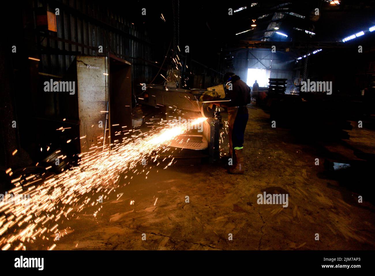 An industrial worker with work tools with Lots of glowing sparks inside ...