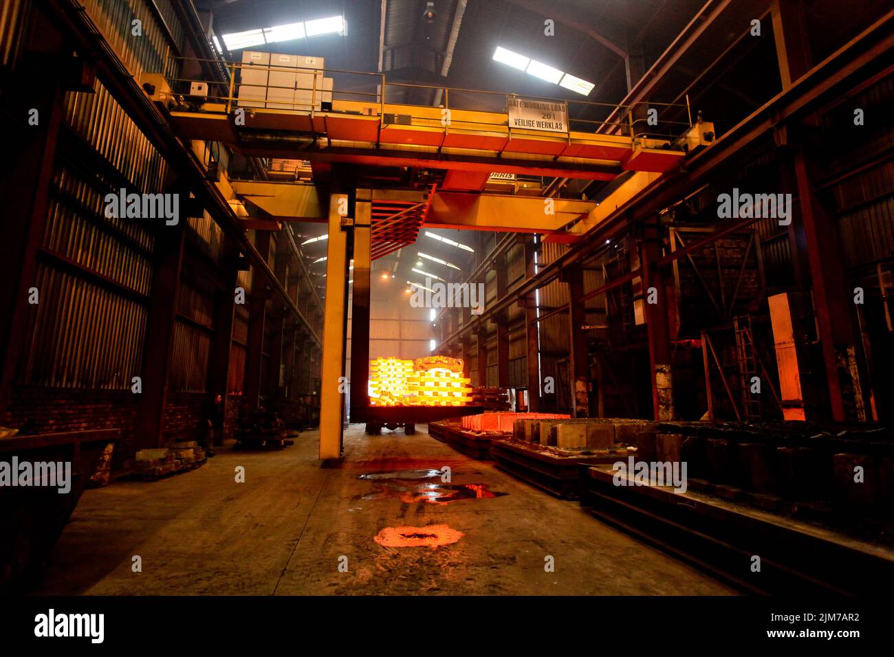 A low angle shot of hot molten forged steel rods outside a furnace ...