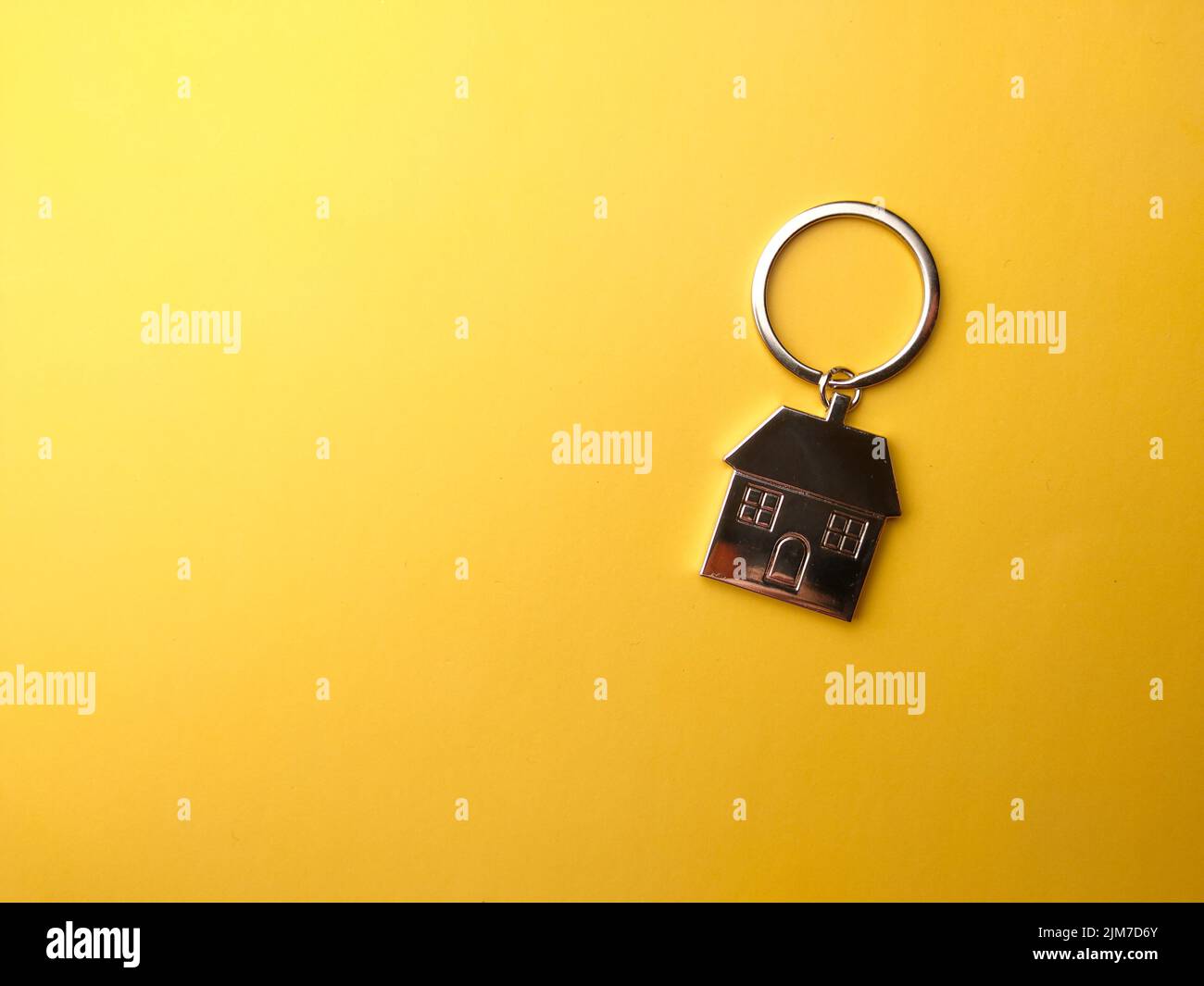 A top view of a house keychain isolated on a yellow background with ...