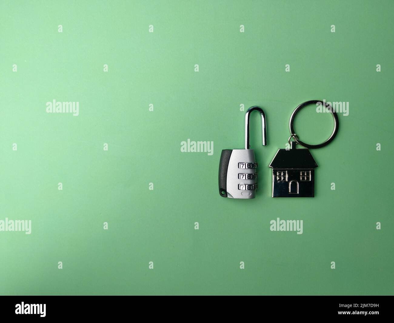 A top view open padlock and house keychain on a green background with ...